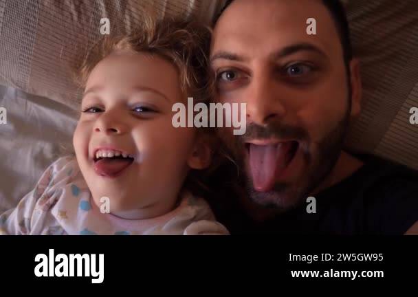 Authentic close up of a dad and daughter making funny faces, looking at ...