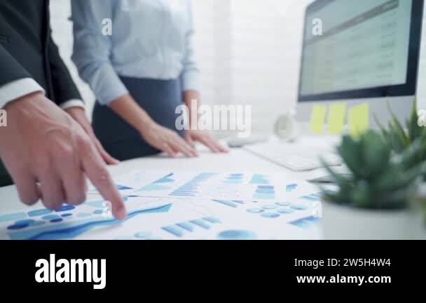 Two business people analysing and looking at diagrams on documents in ...