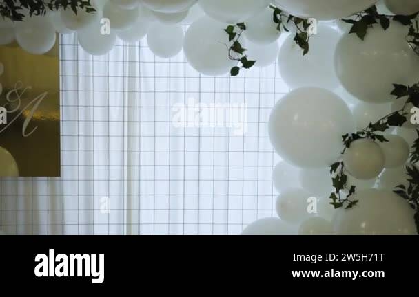 Exquisite wedding arch made of white balloons and branches of a green ...
