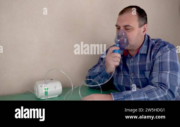 man makes inhalations with the help of nebulizer. patient breathes ...