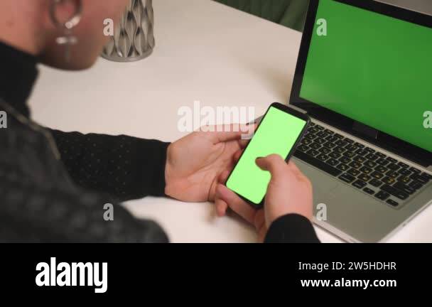 Back view. Close up homosexual man with a manicure use laptop green screen holding phone ...