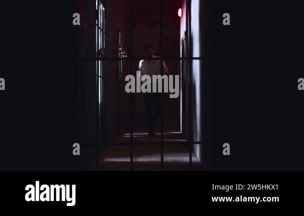 Horror acting - a dangerous male warden walks by the cells in the ...