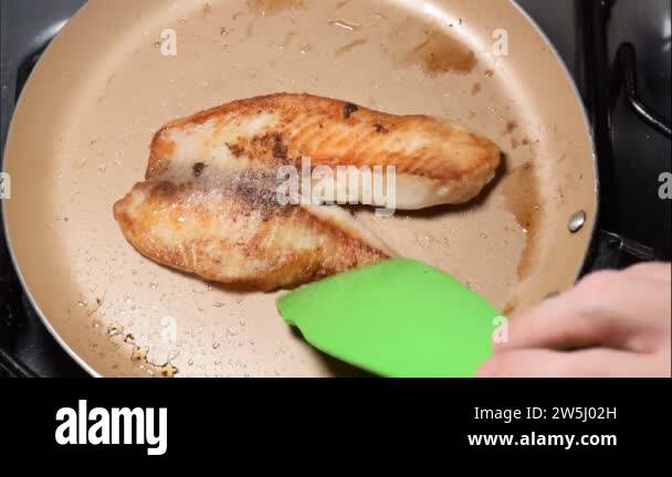 Tilapia fillet (Saint Peter) being fried in butter. Stirring the fish ...