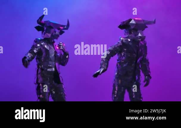 Two shiny bulls in costumes made of mirrors fun dancing on neon blue ...