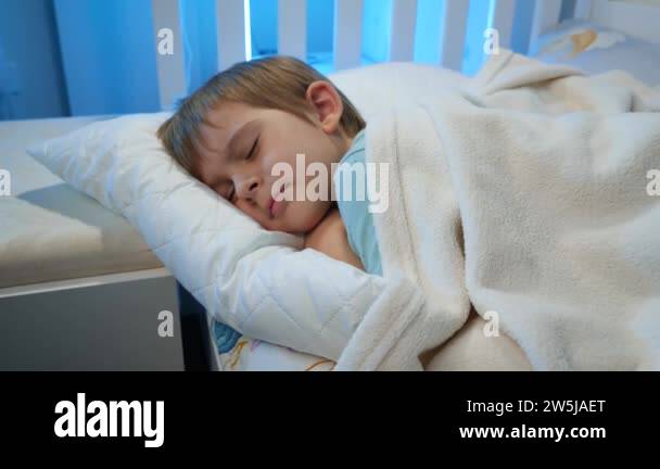 Dolly video of little toddler boy sleeping on bed at his room at night ...