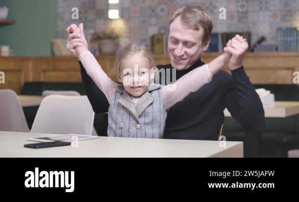 Laughing Caucasian father and cute cheerful daughter showing strength ...