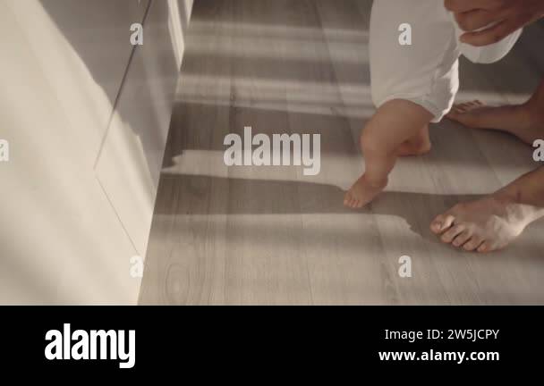Baby taking first steps. The father holds and supports the child and teaches him to walk at home ...