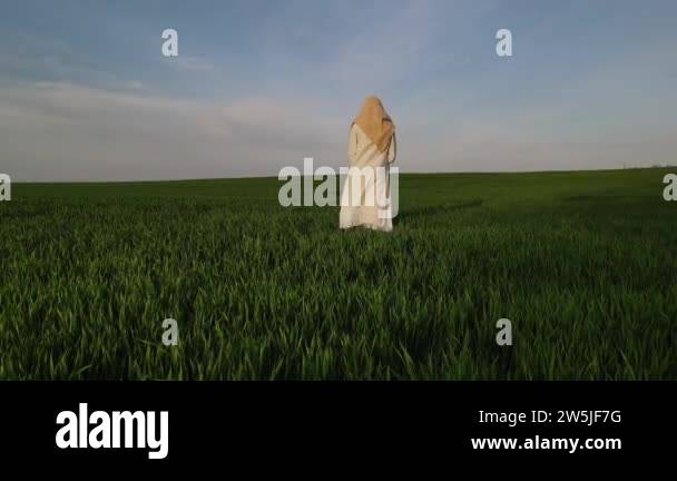 Jesus Christ walks on meadow clothed in his traditional white robe ...