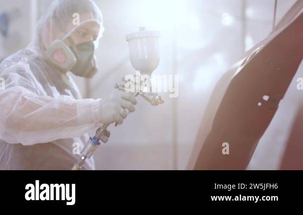 Professional car painter is painting a body work. Male technician is ...
