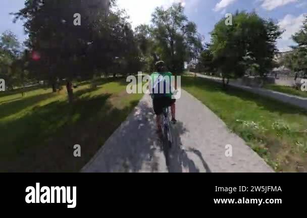 Cycling in the park. The cyclist rides along the path between the trees ...