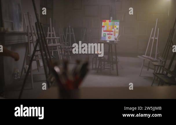 Full slow-motion footage of adult artist in beige shirt entering dark ...