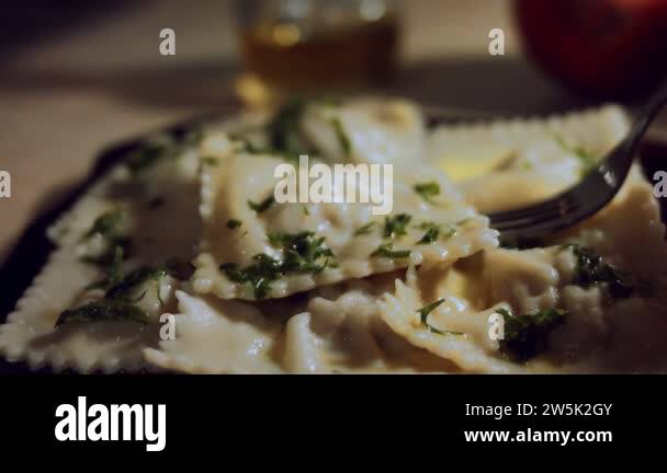 Close-up of fork taking ravioli covered with melted butter and chopped ...