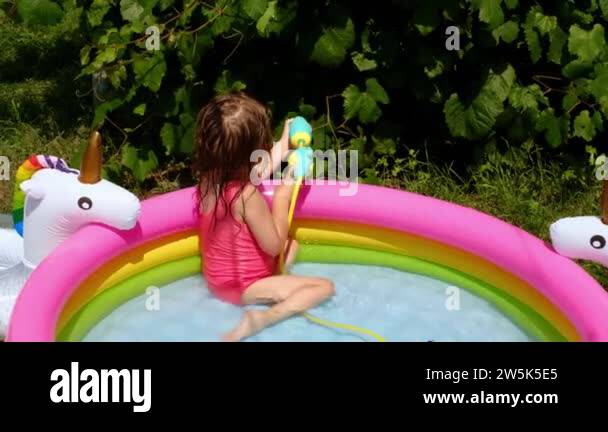 A child is swimming in the pool in the yard and shoots water from a ...