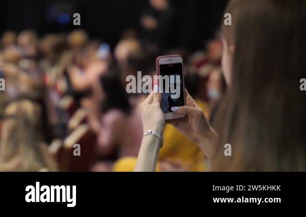 Girl filming model on fashion show catwalk. Smartphone in hands ...