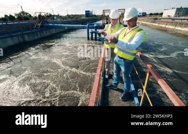 Wastewater operators taking a water sample at a sewage cleaning ...