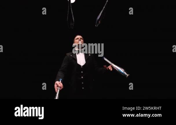 Camera rotates around circus juggler using pins to juggle. A man in a ...
