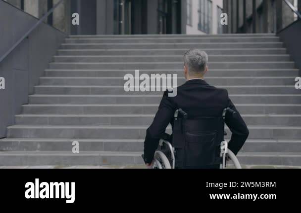 Backside view of male person in suit on wheelchair standing at street ...
