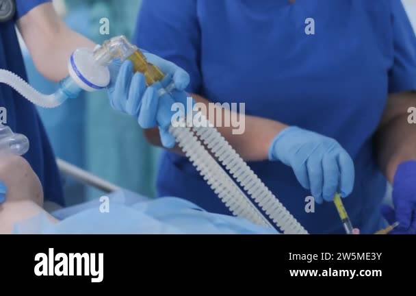 The anesthesiologist in medical gloves prepares female patient for ...