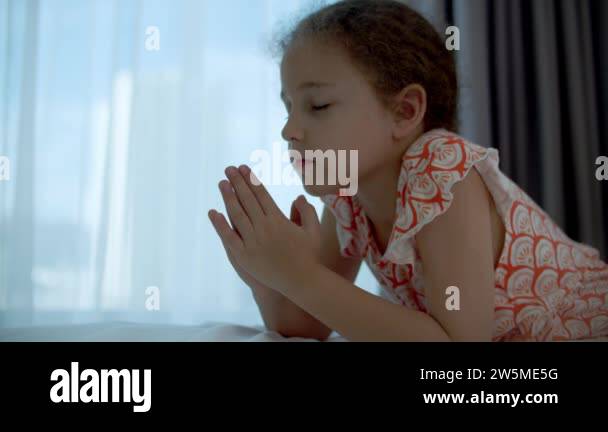 Little girl is praying in her room.Close up portrait of child concept ...