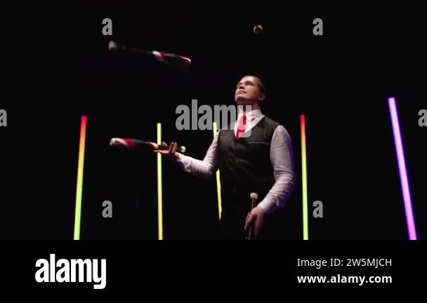 Camera rotates around professional circus performer juggling with clubs ...