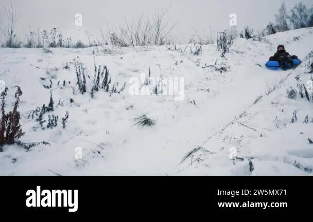 A boy riding a slide on a tubing in winter Park. Snow slide in the ...