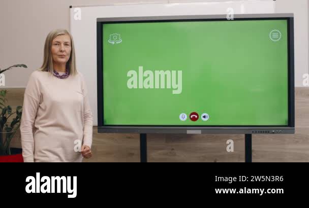 Female teacher talking and turning to interactive screen with template ...