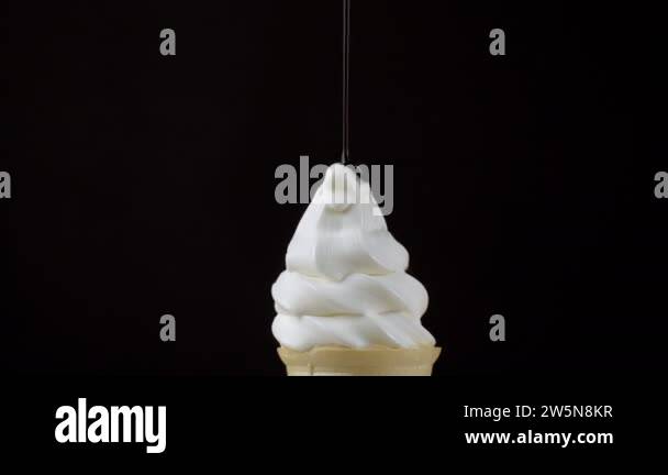 Vanilla flavor ice cream cone with tempting chocolate syrup pouring ...