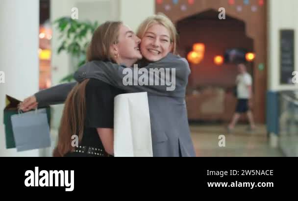 Stylish friends are walking in the mall, laugh and hugging. Happy ...