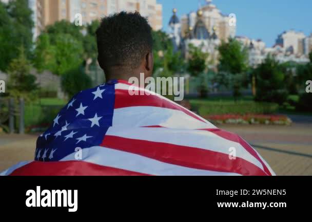 Back view patriot afro-american man walking street with American flag ...