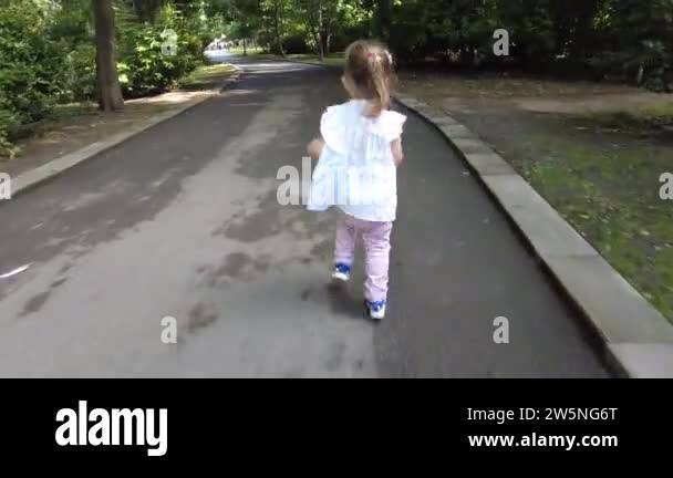 Little girl running outside in the park. Playing chase with his father ...