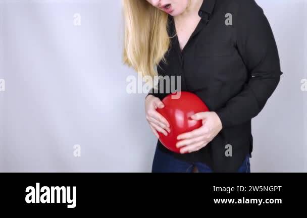 Bloating and flatulence concept. The woman holds a red balloon near the ...