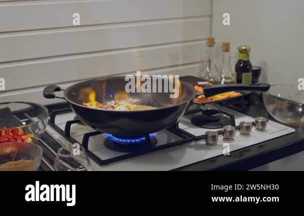 Roasting vegetables and chicken in a wok over a fire. Cooking Asian ...