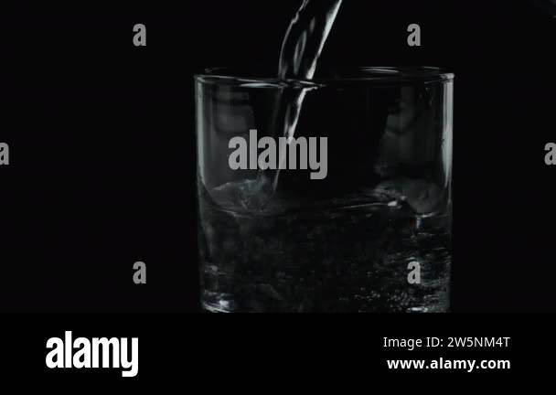 Mineral water flow into glass, pour drinking water into glass on black background Stock Video ...