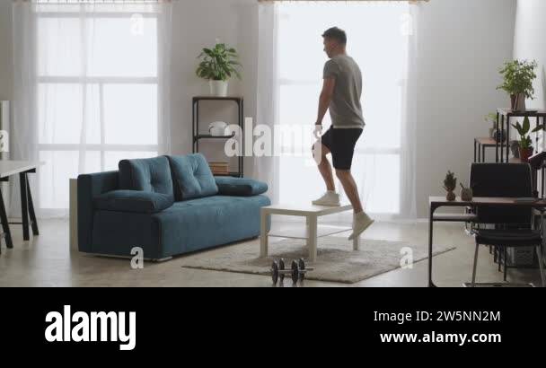 sport workout indoors, man is training alone at home, using furniture ...