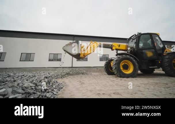 Tractor moves rubble to truck. Excavator-loader rakes rubble from pile ...