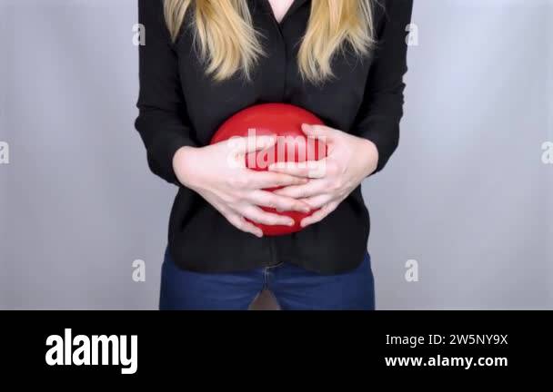 Bloating and flatulence concept. The woman holds a red balloon near the ...