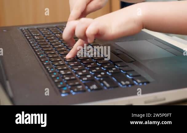 Closeup of little boy typing and pressing buttons on laptop keyboard ...