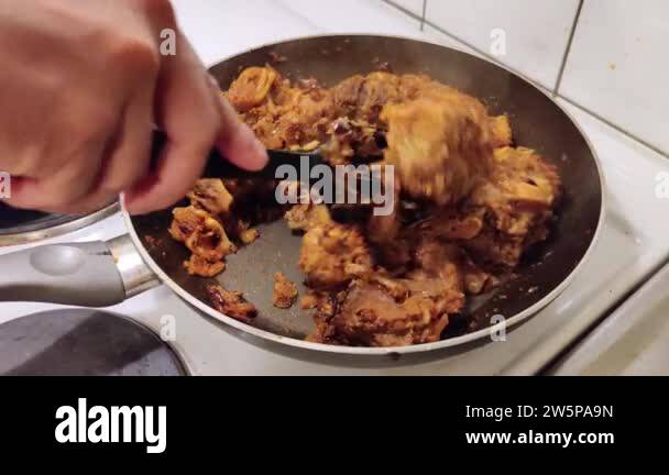 The mutton meat is being fried in a black pan with high heat stir for ...