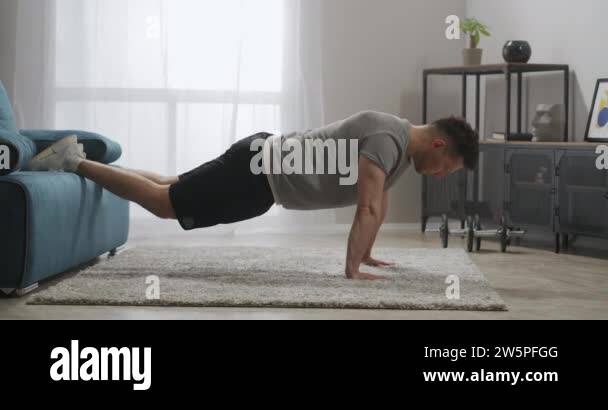 strong man is doing physical exercise for biceps, push-ups in living ...