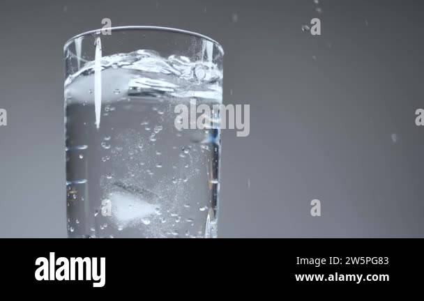 Throw pieces of ice in a glass of carbonated water. Air bubbles rise from the top of the water ...