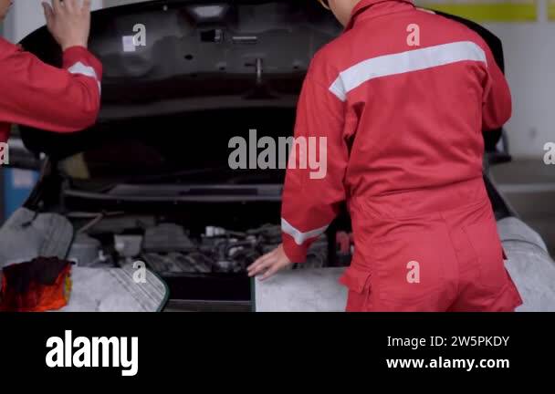 worker men in factory dress opening front car and repairing a car ...