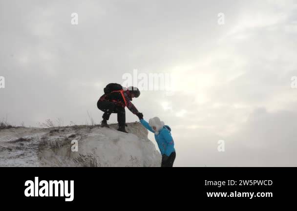 Tourist climbers man and woman stretch out their hands to each other, help climb to the top of ...