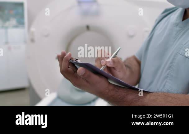 Mid-section PAN of unrecognizable male tech filling medical form in CT ...