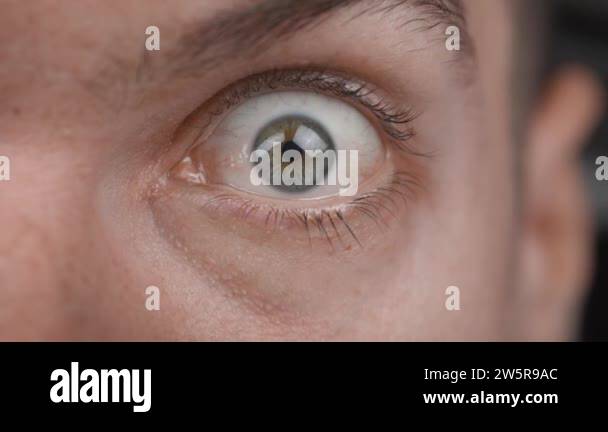 Extreme close up of surprised male opens his eye wide and stares at the ...