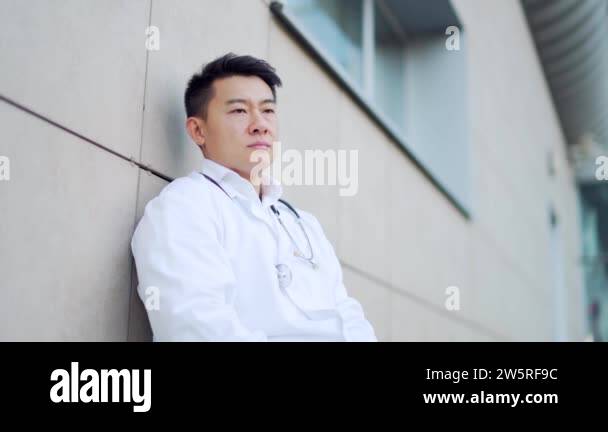 portrait stressful Asian doctor sitting or standing outside a hospital ...