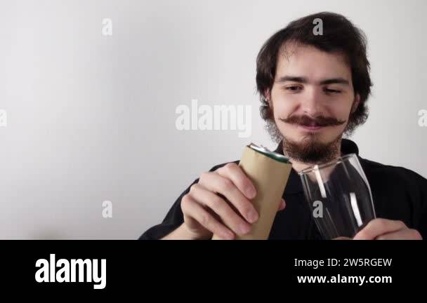 Man is opening tin can of beer then pouring it into glass and drinking ...