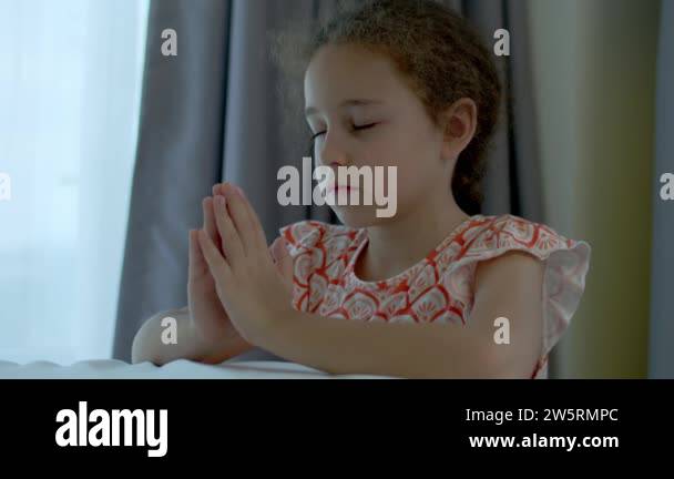 Little girl is praying in her room.Close up portrait of child concept ...