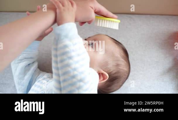 Mother combing tiny hairs on her newborn babys head as she wakes up ...