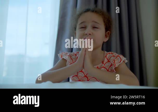 Little girl is praying in her room.Close up portrait of child concept ...