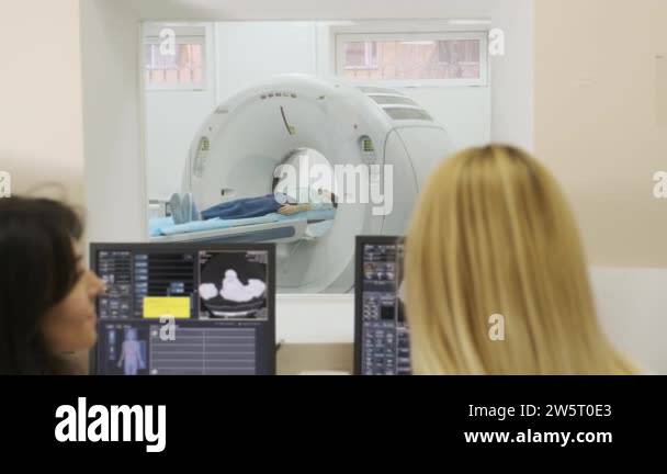 Two qualified radiologists examines female patient who is lying under ...